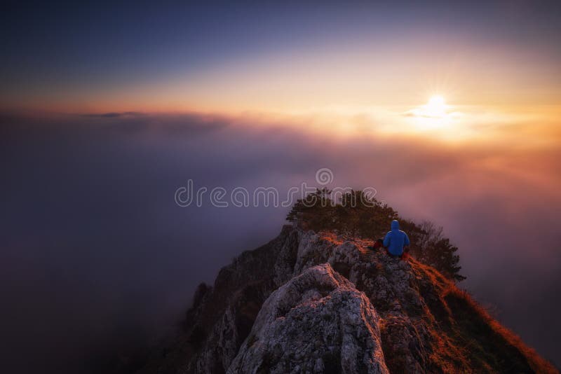 Dramatic Silhouette of Man Sitting on Mountain Ridge Over Looking Misty ...