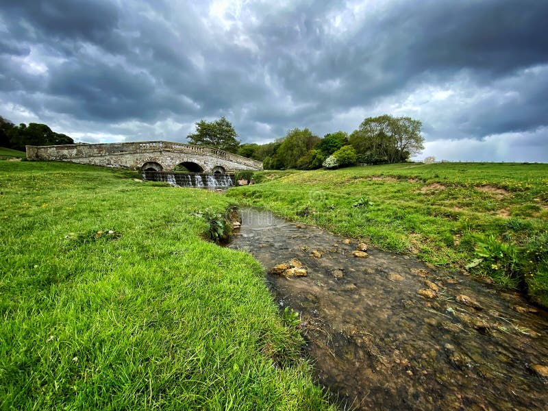 Dramatic Skies Over Pack Bridge with Stream in Foreground Stock Photo ...