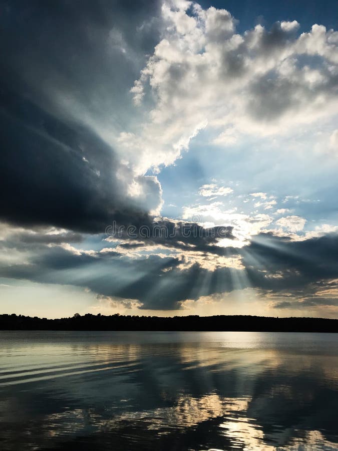 Dramatic Sky with Sun Rays Over a Tranquil Lake Stock Photo - Image of ...