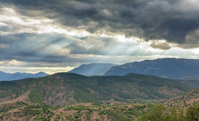 Dramatic Stormy Sky with Sun Rays through the Clouds Over a Hilly ...