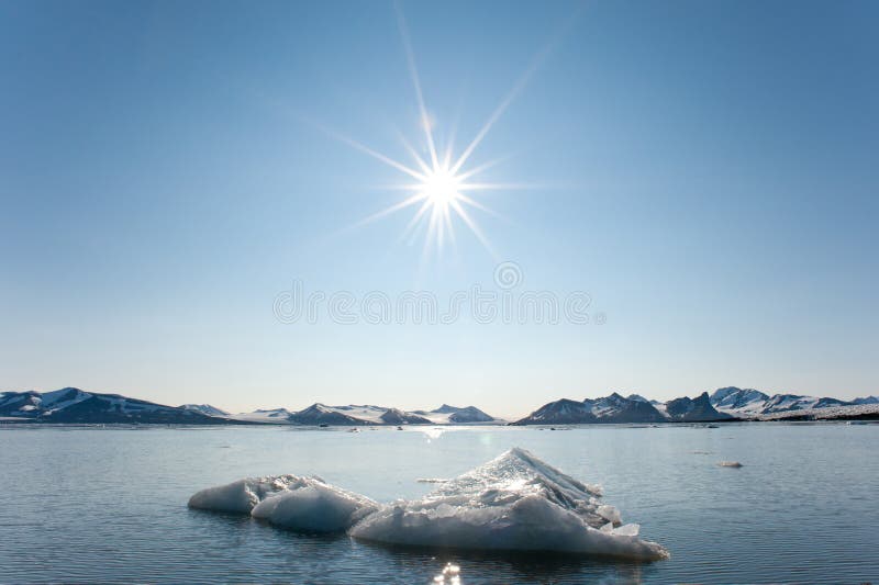 A Dramatic Sun Burst Over Arctic Mountains and a Floating Iceberg in ...