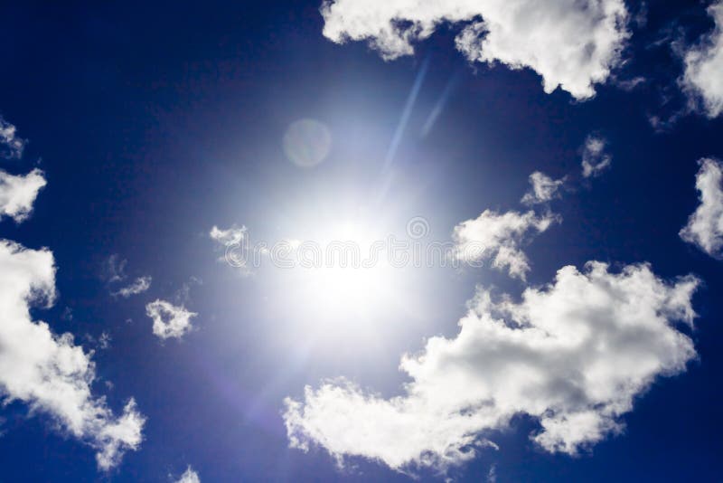 Dramatic Sun Flare with Fluffy Clouds into Deep Blue Sky, High C Stock ...