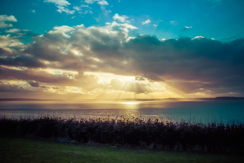 A Dramatic Sunset through the Clouds Over the Ocean with Rays of Light ...