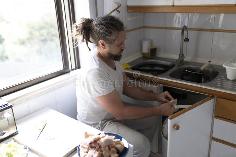 Man Throwing Chicken Bones in Garbage Bag while Cooking in Kitchen ...