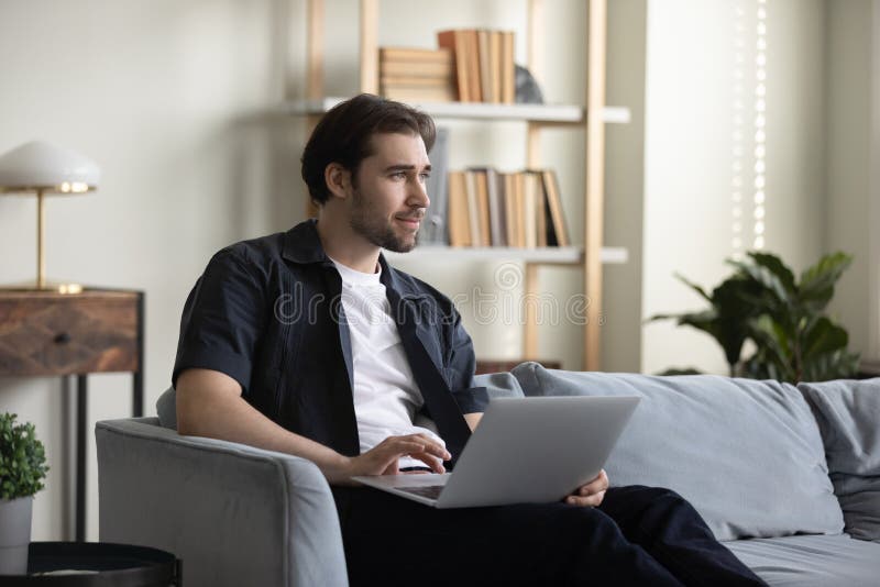 Dreamy Smiling Young Man Using Computer at Home. Stock Image - Image of ...