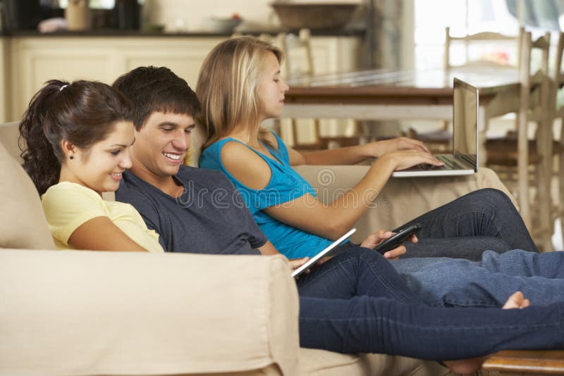 Drie Tieners Die Op Sofa at Home Using Mobile Zitten Telefoneren ...