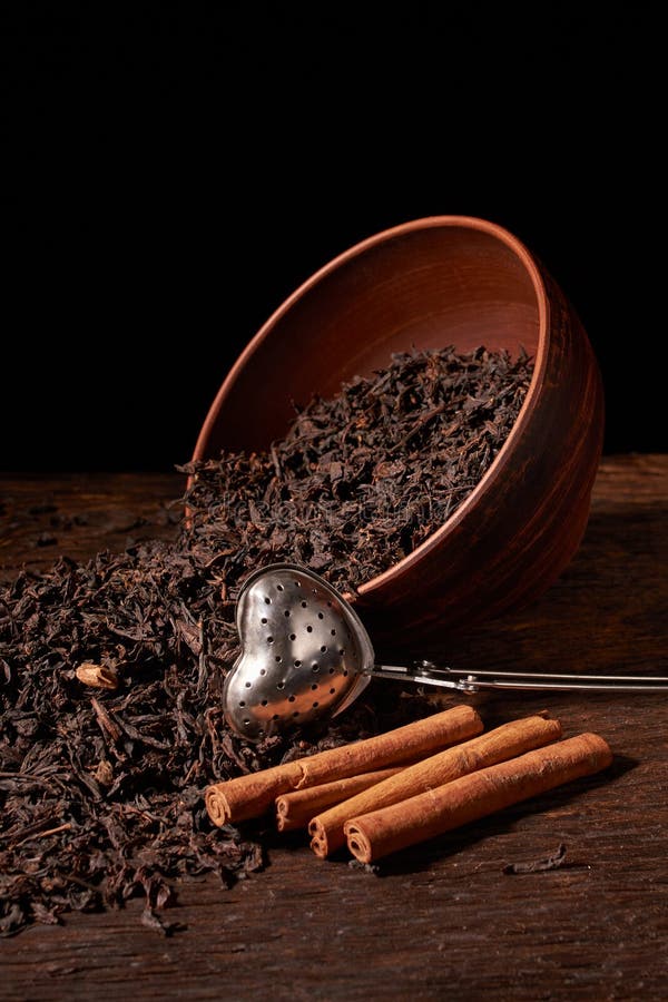 Dried Black Tea in Clay Bowl with Sticks of Cinnamon and a Tea Strainer ...