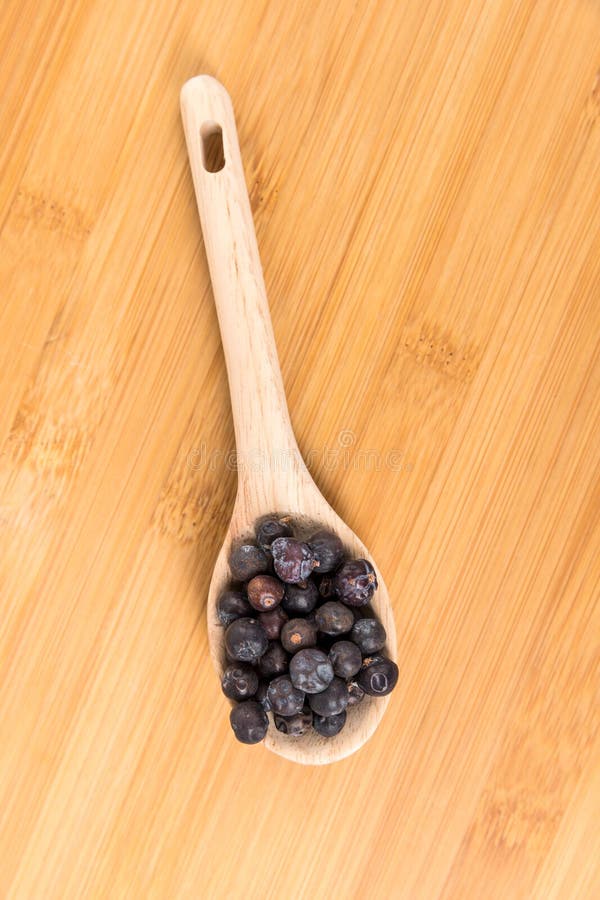 Dried Juniper Berries in a Wood Spoon Over Wood Board Top Down Stock ...