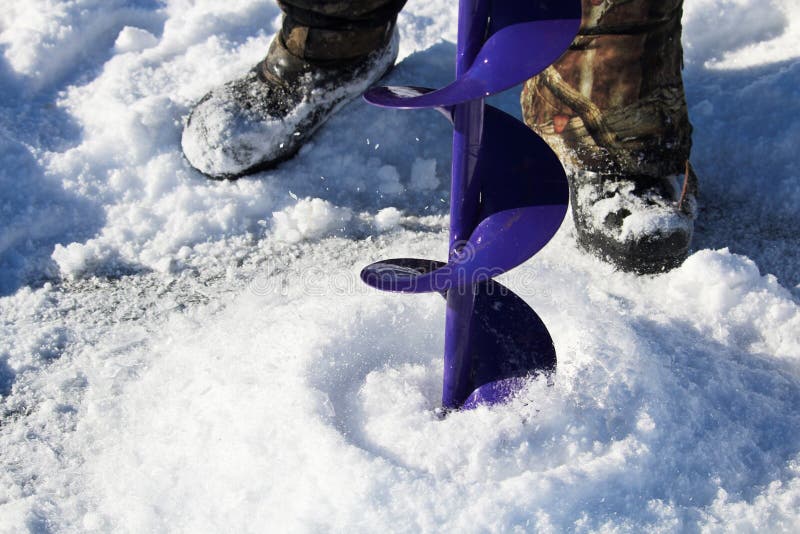 Drilling an Ice Fishing Hole with a Boots in the Background Stock Photo ...