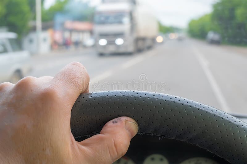 Driver`s Hand on the Steering Wheel of a Car that is Driving on the ...