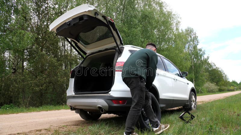 Driver Takes Out Spare Tire from the Trunk of Car. Replacing a Damaged ...