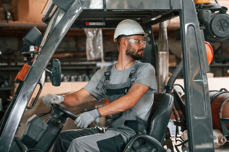 Driving the Forklift. Young Factory Worker in Grey Uniform Stock Photo ...
