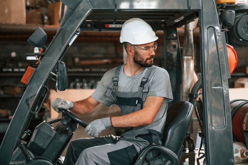 Driving the Forklift. Young Factory Worker in Grey Uniform Stock Photo ...
