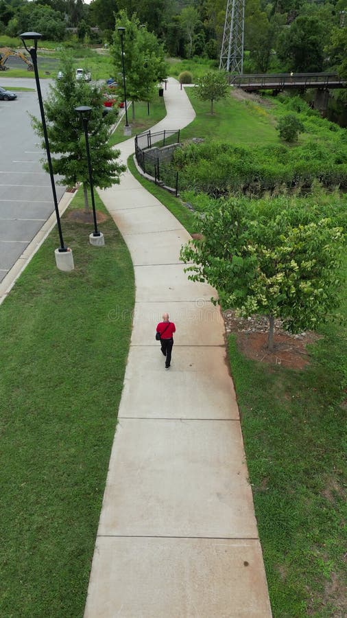 Drone Flying Over a Bald Man Walking in a Garden Track with Small Pond ...