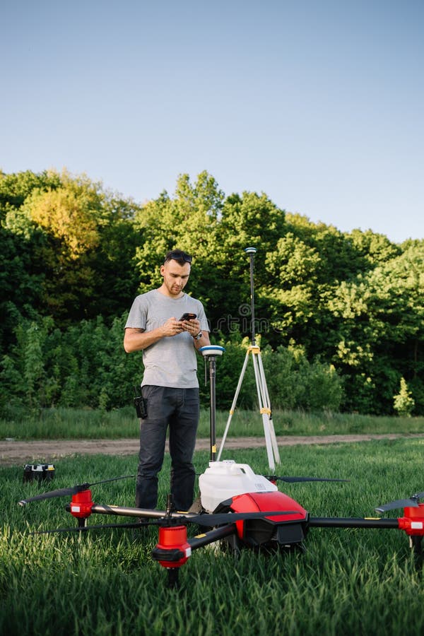 A Drone Pilot Configuring His Drone in a Field with and Irrigation ...