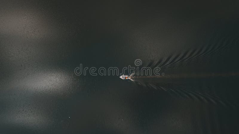 Drone View of a Boat Sailing Across the Dark Water of the Lake Stock ...
