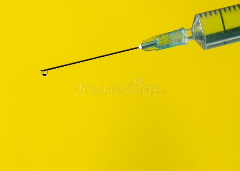 A Syringe with a Yellow Substance and in the Background Four Test Tubes ...