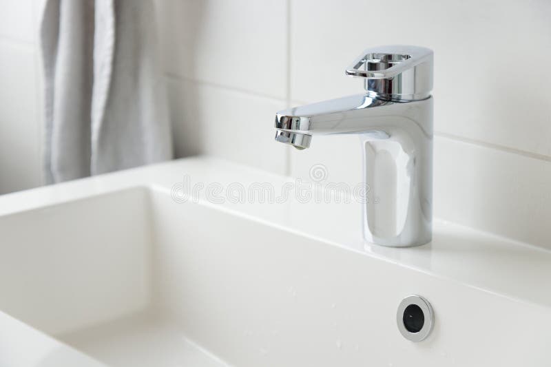 A Drop of Pure Water Dripping from the Tap in the White Modern Bathroom ...