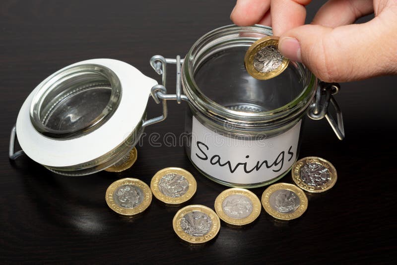 Dropping One Pound Coin into Jar for Savings Stock Photo - Image of ...