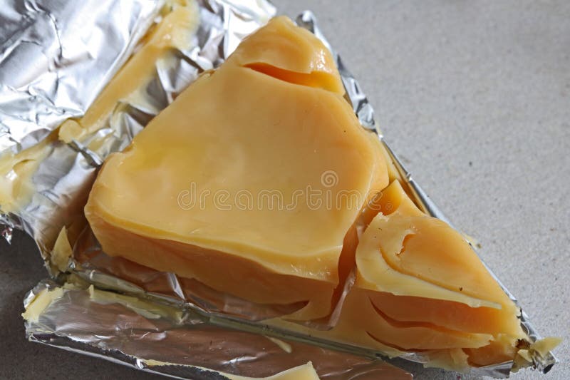 DRY CRACKED PROCESSED CHEESE WEDGE in a FOIL WRAPPING Stock Photo ...