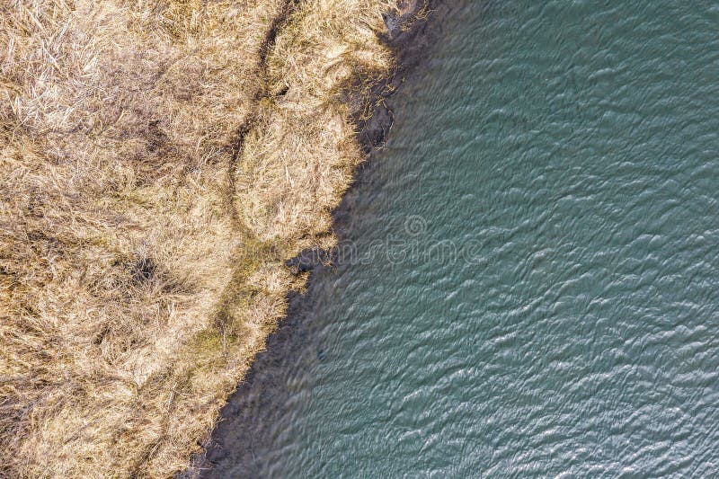 Dry Grass on River Shore and Water with Sky Reflection. Natural ...