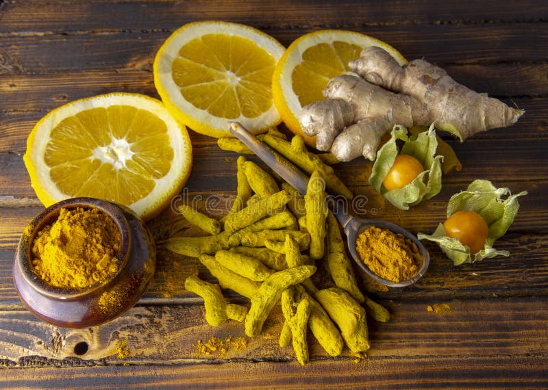Dry Turmeric Root, Turmeric Powder, Ginger and Citrus on a Wooden ...