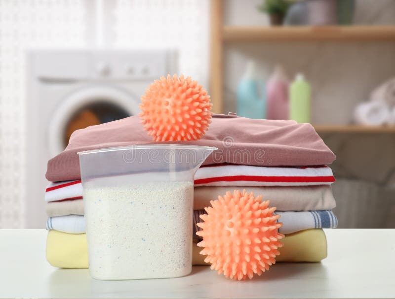 Dryer Balls, Detergent and Stacked Clean Clothes on Marble Table in ...