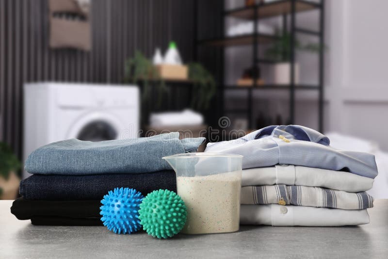 Dryer Balls, Detergent and Stacked Clean Clothes on Table in Laundry ...