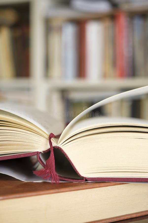 Open Book or Textbook on a Pile of Closed Books in Front of a Bookcase ...