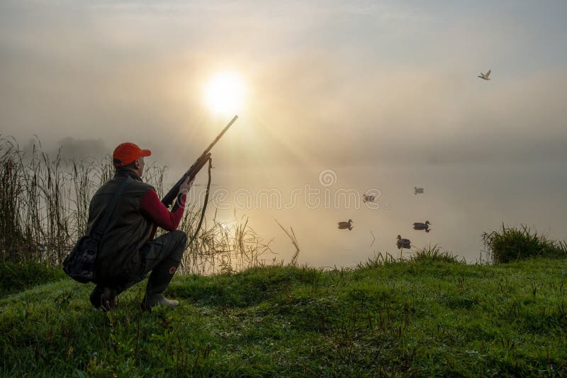 Waterfowl Hunter Sitting at Riverside during Duck Hunting at Sunrise ...