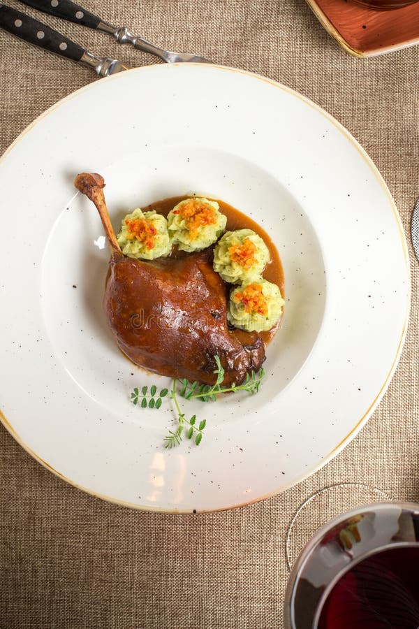 Duck Leg Confit with Mashed Potato and Glass of Red Wine on the Table ...
