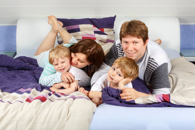 Due Bambini E Genitori Divertendosi a Letto Immagine Stock - Immagine ...