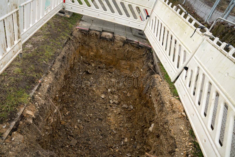 A Dug Trench Fenced with Plastic Barriers on a Section of Sidewalk ...