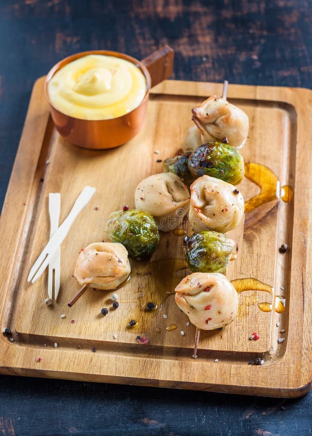 Dumplings and Brussels Sprouts on Skewers with Cheese Sauce Stock Photo ...