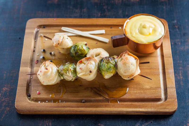 Dumplings and Brussels Sprouts on Skewers with Cheese Sauce Stock Photo ...