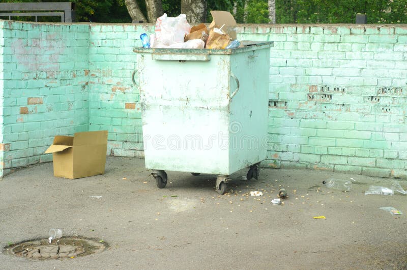 A Dumpster with Overflowing Garbage and an Empty Box in a Fenced Waste ...