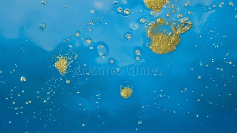 Dynamic Drops of Yellow Glitter in Blue Oil or Ink Diffusing through ...