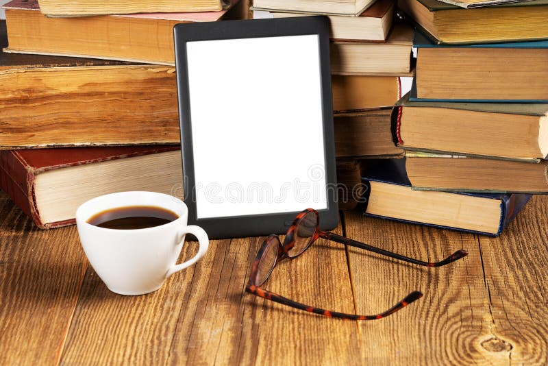 E-reader and Stacks of Vintage Books on the Desk. Glasses and a Cup of Coffee.Electronic ...