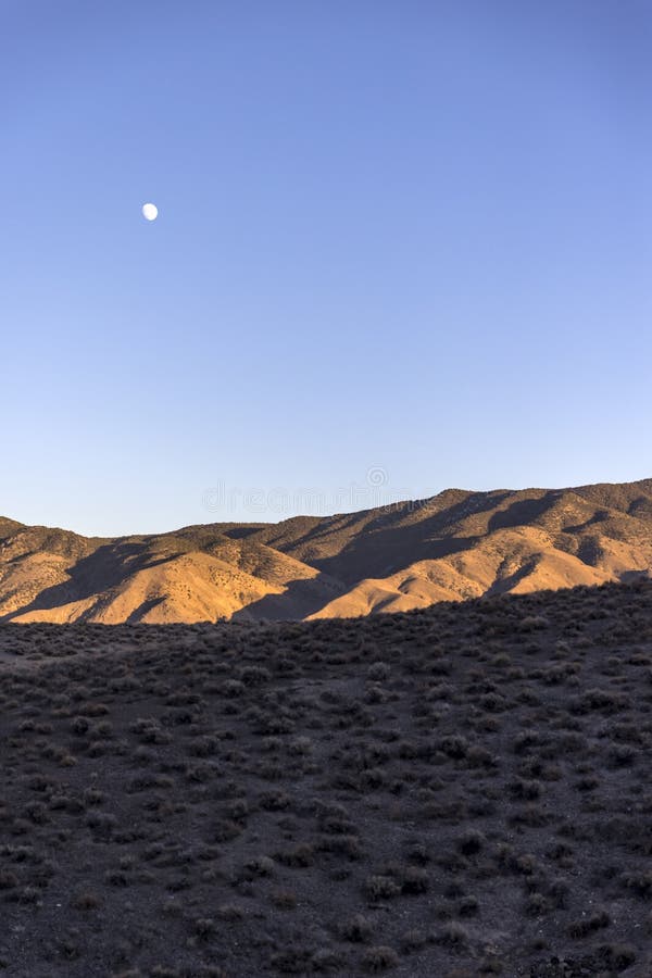 An Early Moon Shines High Over the Mountains during the Sunset Evening ...