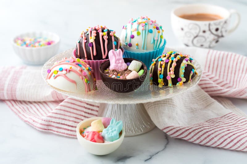 Easter Hot Chocolate Bombs on a Pedestal Stand with a Cup of Hot Cocoa ...