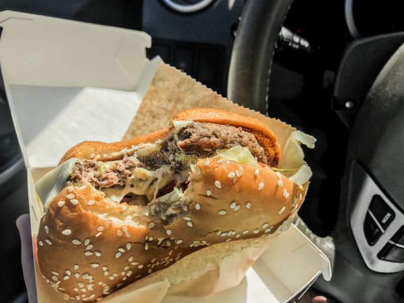 Eating while Driving: a Bitten Burger in the Hands Inside the Car ...