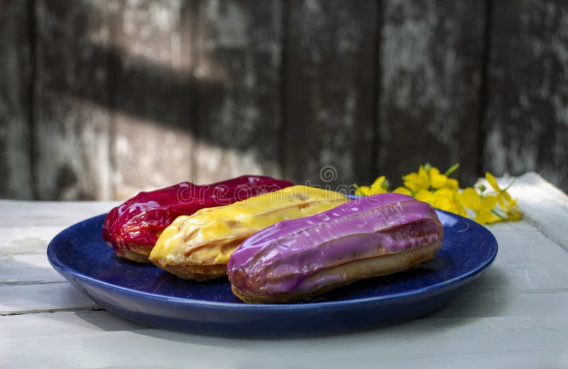 Eclairs of Different Colors on a Blue Plate Stock Photo - Image of ...