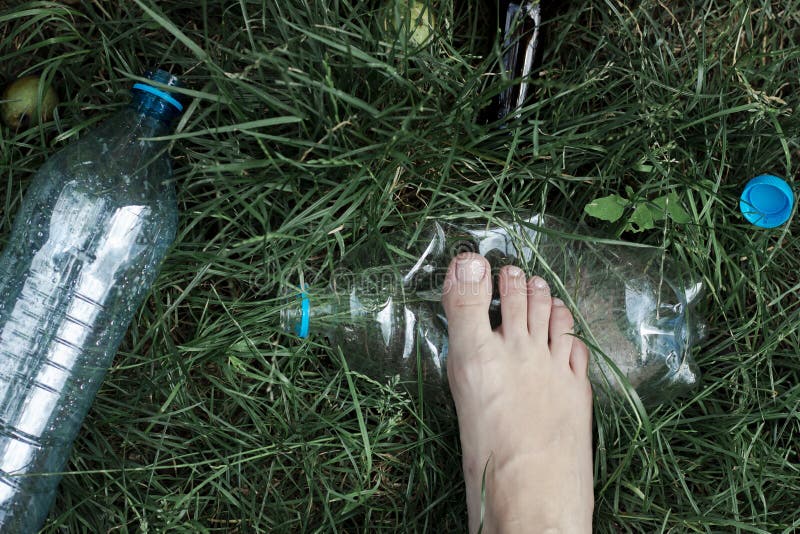 Ecology Concept. Human Foot Crushes a Plastic Bottle on Grass. Stock ...