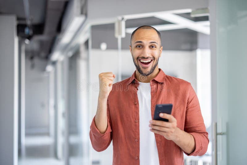 An Ecstatic Man Celebrates a Win, Holding His Smartphone in a Modern ...