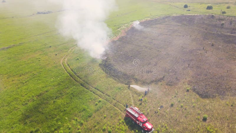 At the Edge of the Field, a Fire Engine and a Fireman are Putting Out ...