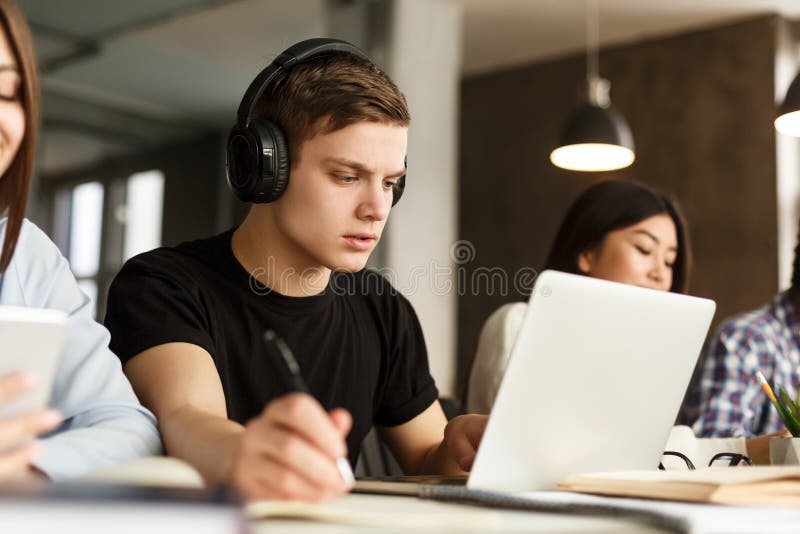 Education Concept. Concentrated Guy Doing Homework in Library Stock ...