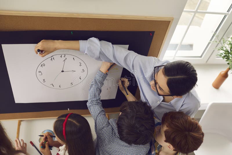 Female Teacher Explaing Clock Time To Elementary Student Children in ...