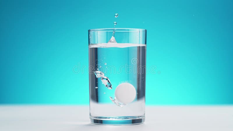 Effervescent Tablet Falling into Glass of Pure Water Standing on Table ...