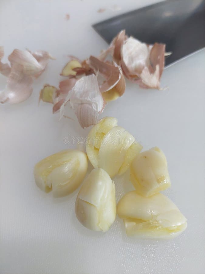 Efficient Kitchen Prep: Peeled Garlic on White Plastic Chopping Board ...