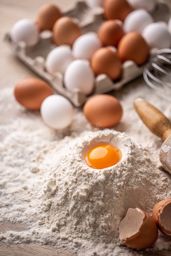 Egg Yolk on Top of a Pile of Flour with More Eggs and Egg Shells in ...